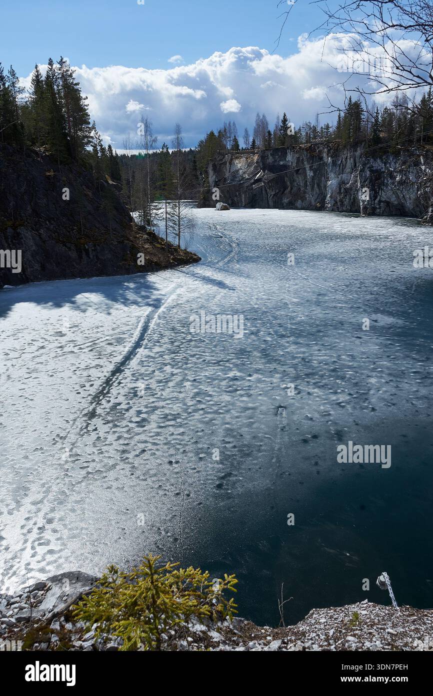 Ruskeala marble quarry in spring. Frozen lake surrounded by rock cliffs ...