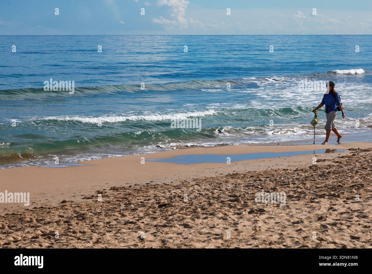Alicante, Spain- January 13, 2026: Young woman walking by the shore on ...