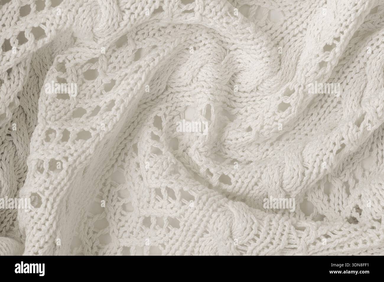 White knitted lace fabric with openwork pattern and soft folds, textile ...