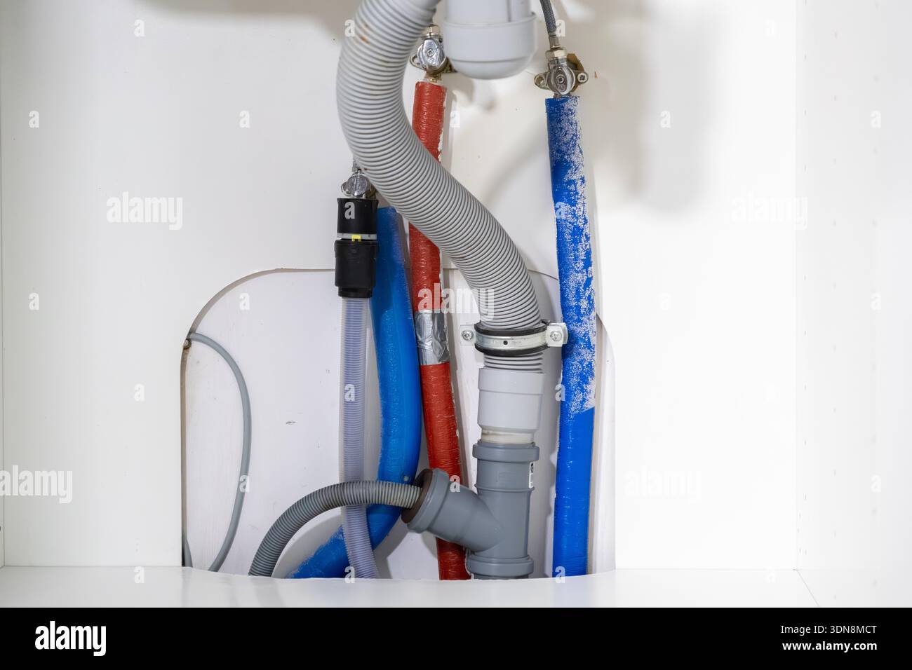 Close-up of residential plumbing pipes and a corrugated drain hose ...