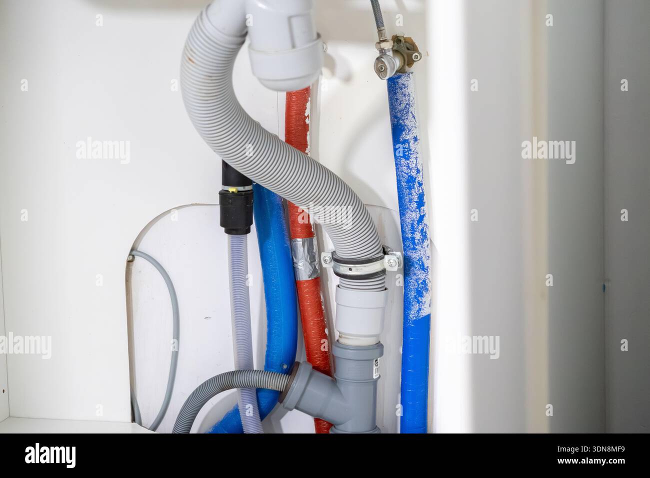 Detailed view of plumbing connections showcasing drain hoses, insulated ...