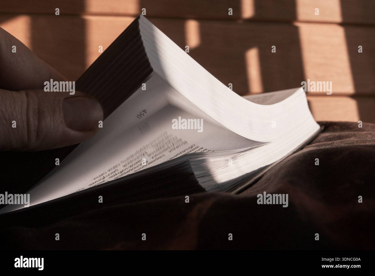 Hand turning pages of open book with visible printed text in warm ...