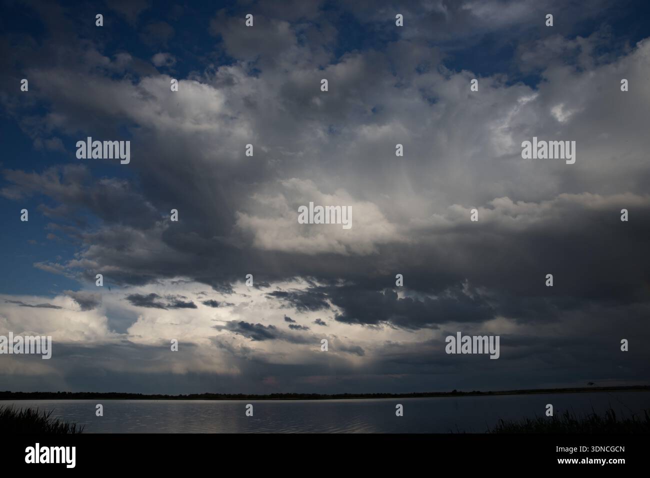 Dramatic storm clouds over calm lake with dark sky and changing weather ...