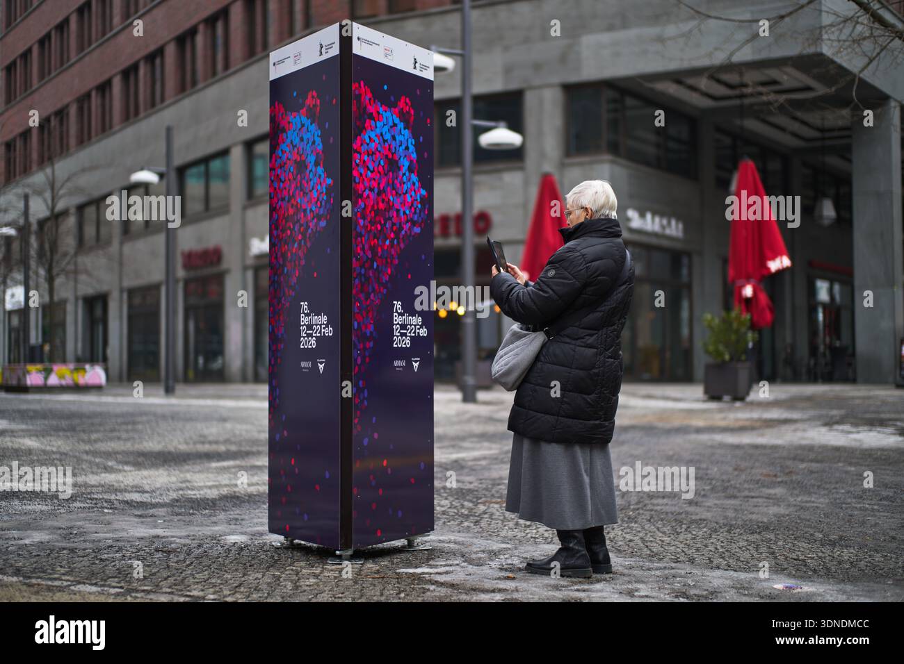 A woman takes a photo of a Berlinale poster ahead of the International ...
