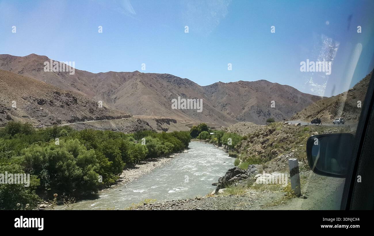 A river winds through Panjshir Valley, Afghanistan, with green trees ...