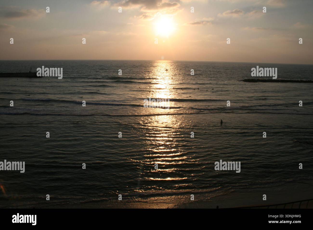 Glistening golden sunset over the ocean with distant figures in the ...