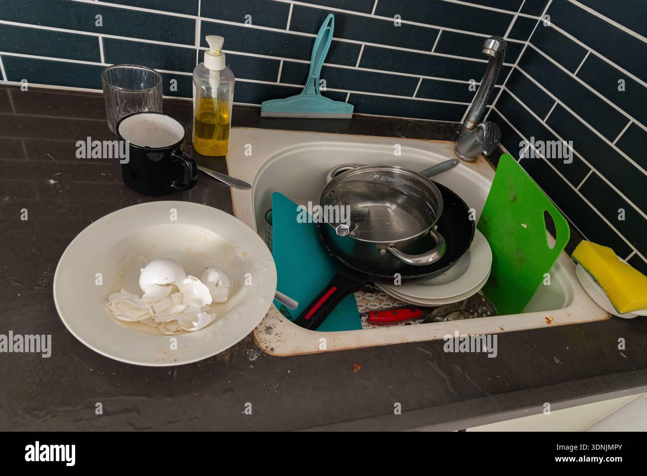 Dirty kitchen sink filled with unwashed dishes, utensils and cleaning ...