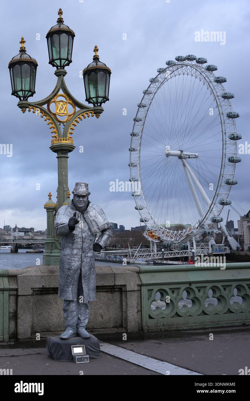 A street artist performs on Westminster Bridge with the London Eye ...