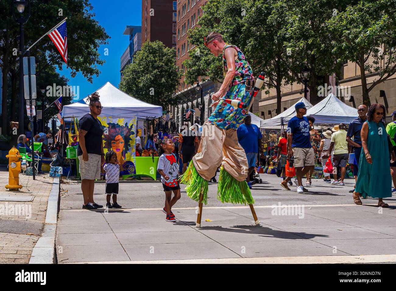 Raleigh, North Carolina, USA. A stilt walker entertains a child during ...