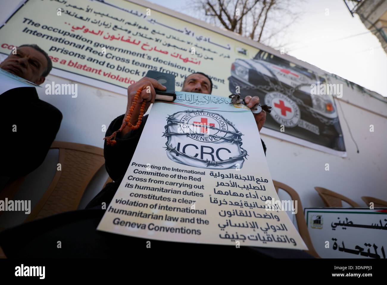 A protester holds a poster featuring the International Committee of the ...