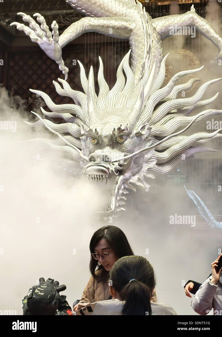 A silver sculpture of a Chinese dragon emits vapor at the entrance of ...
