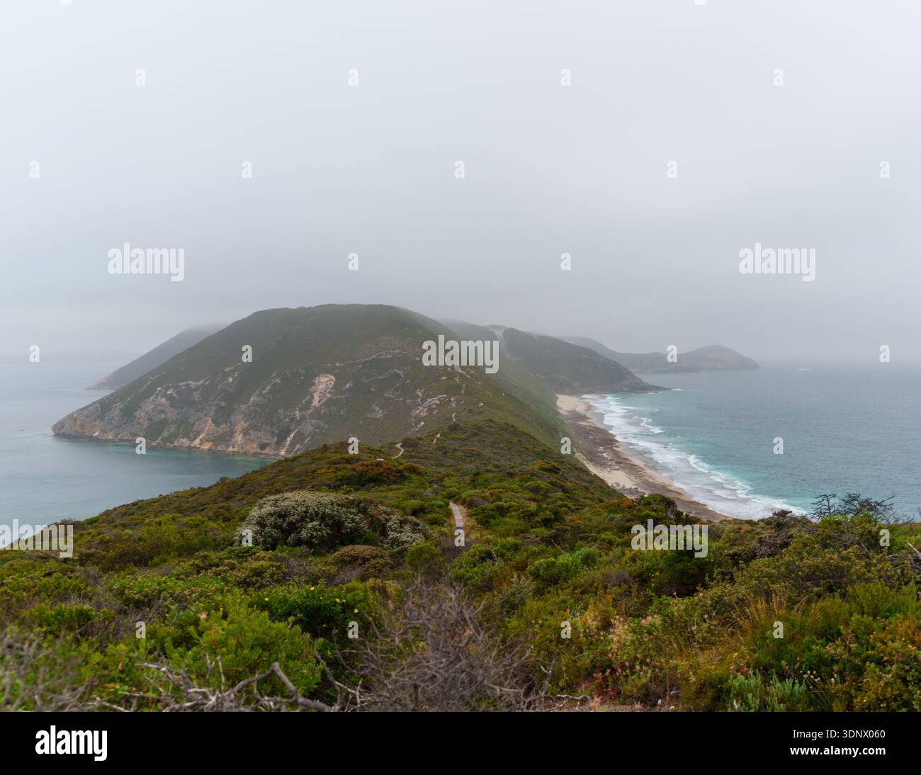 A misty coastal landscape overlooks the rugged ridge line and shoreline ...