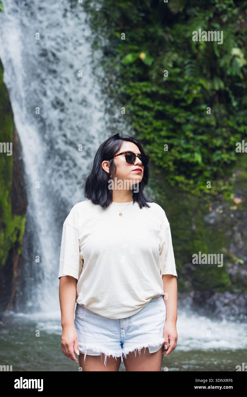 A woman strolls through the lush greenery of Mindo, Ecuador, enjoying ...