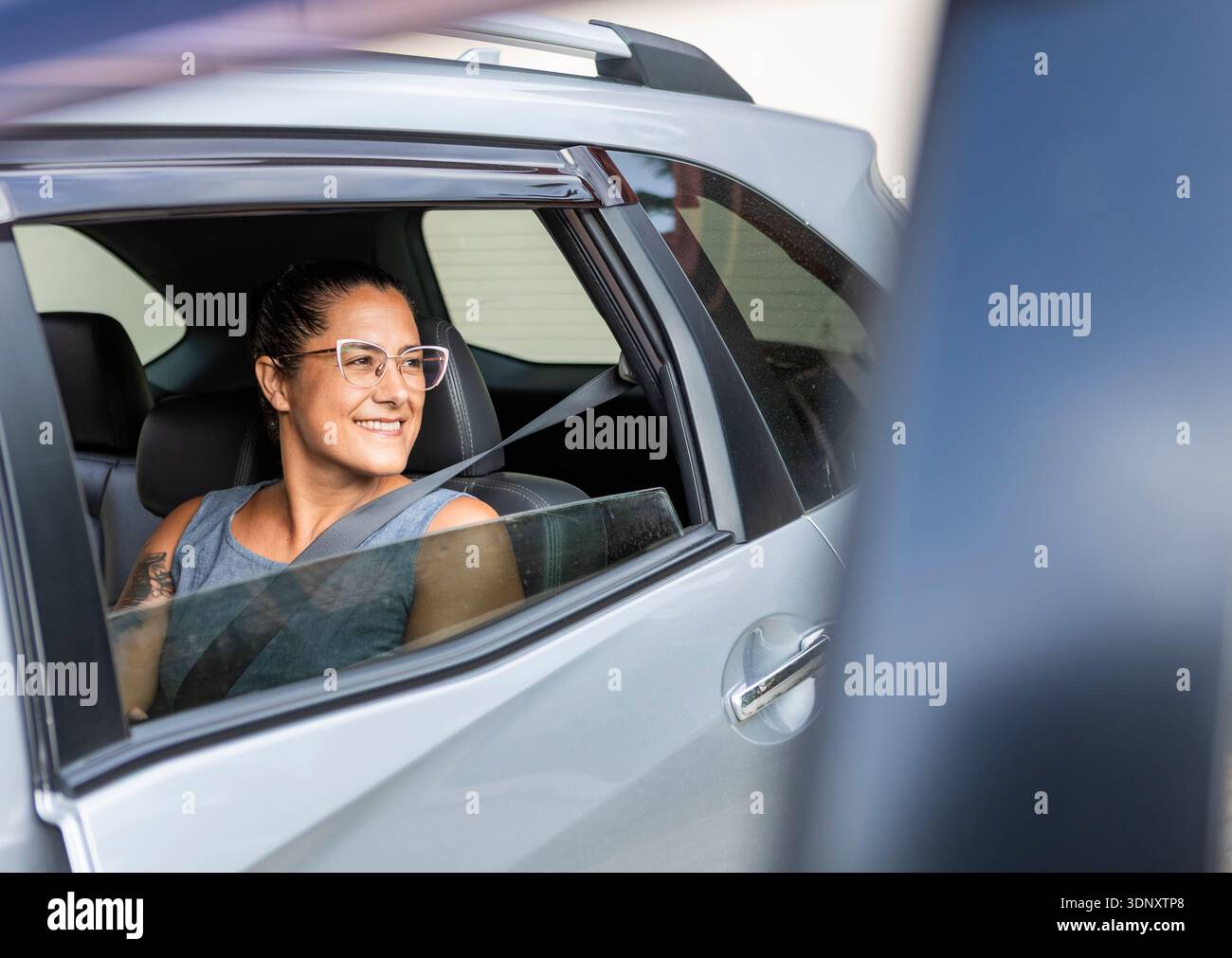 A businesswoman sits in a car, looking content and confident. Her ...