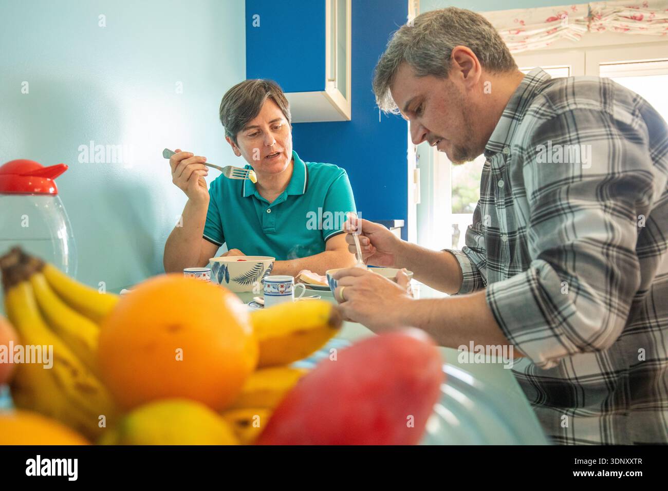 Two people enjoy a relaxed breakfast at home, engaging in light ...