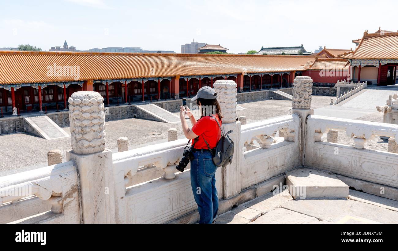 A visitor photographs the historic architecture of the Forbidden City ...