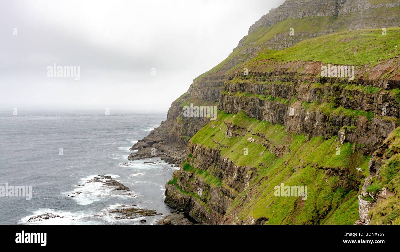 Majestic cliffs of Vagar Island in the Faroe Islands reveal layers of ...
