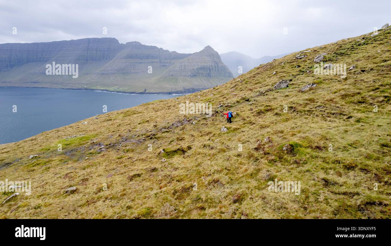 Hikers standing on the grassy slopes of Villingardalsfjall, taking in ...