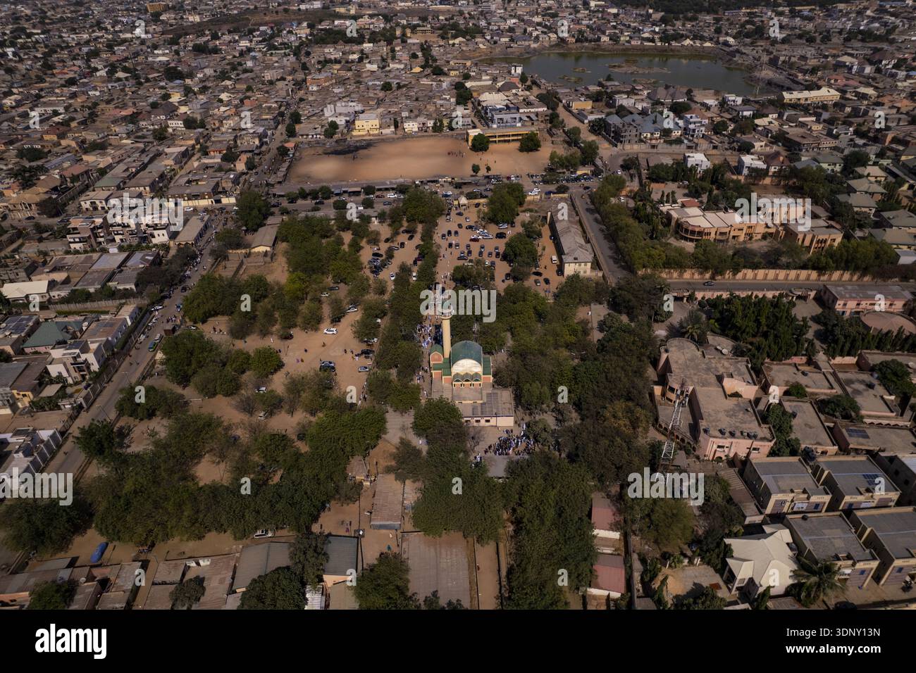 Aerial view of a mosque surrounded by dense trees and urban sprawl ...