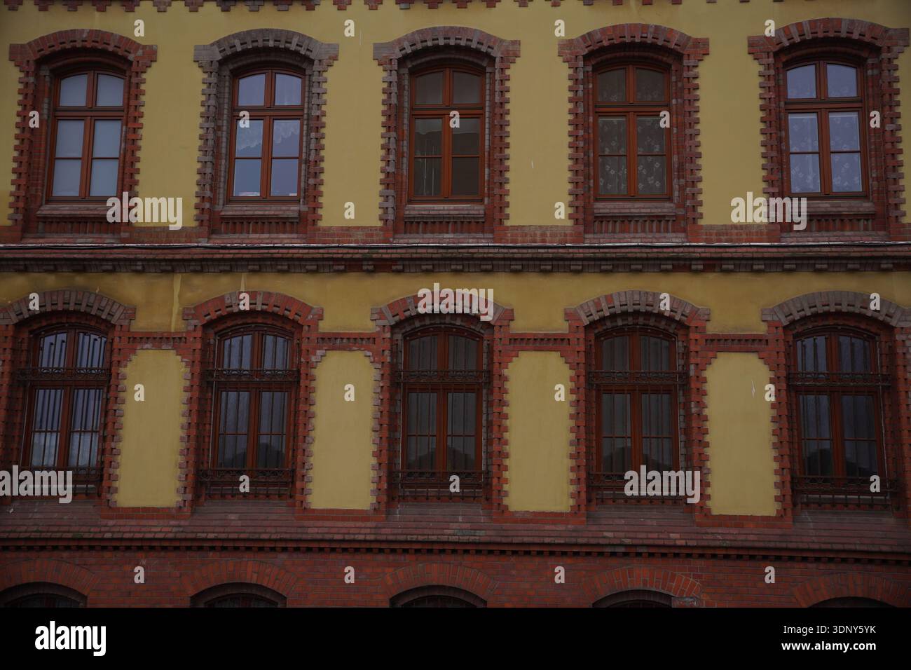 Elegant historic building facade with yellow plaster walls, ornate red ...