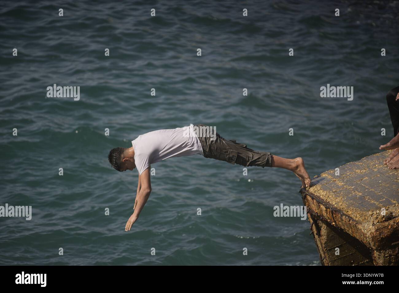 Children swim near the war-damaged port of Gaza, a scene reflecting ...