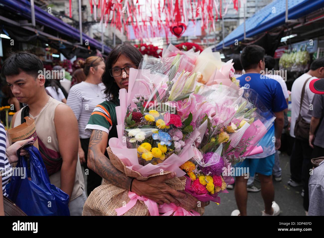 A man carries a bouquet of flowers at a market in Manila, Philippines ...