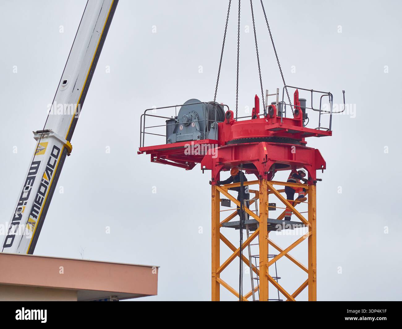 Construction Crane Assembly With Workers Atop Tower During Industrial ...