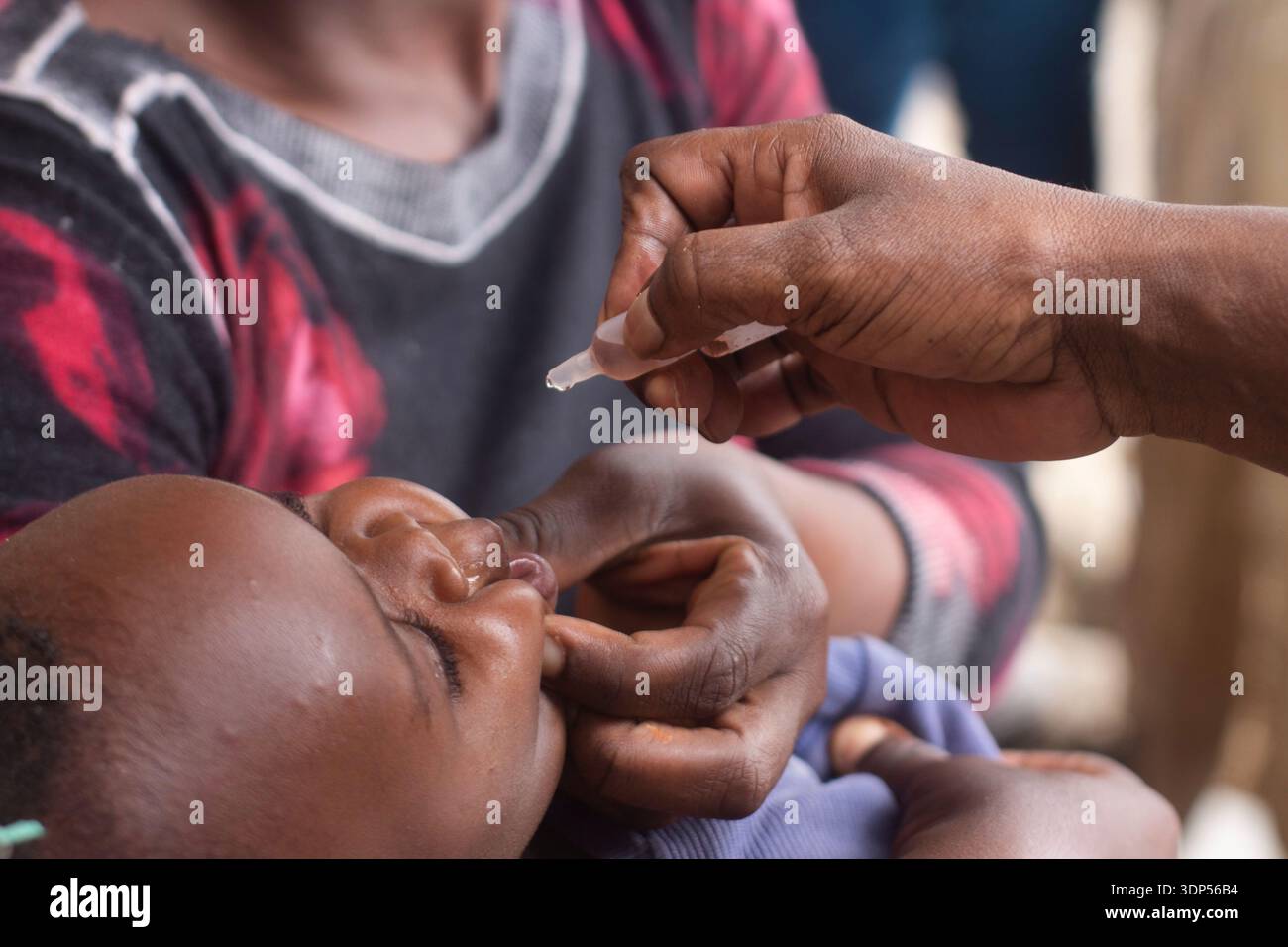 A healthcare worker administers polio vaccine to a child in the ...
