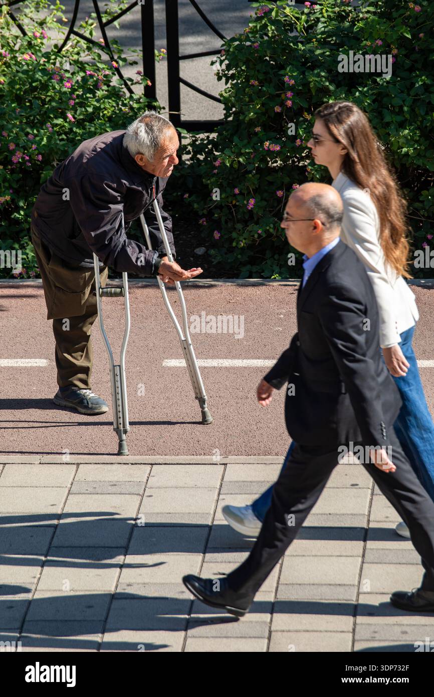 People passing one-legged beggar in front of Mosque of Namazgah in ...