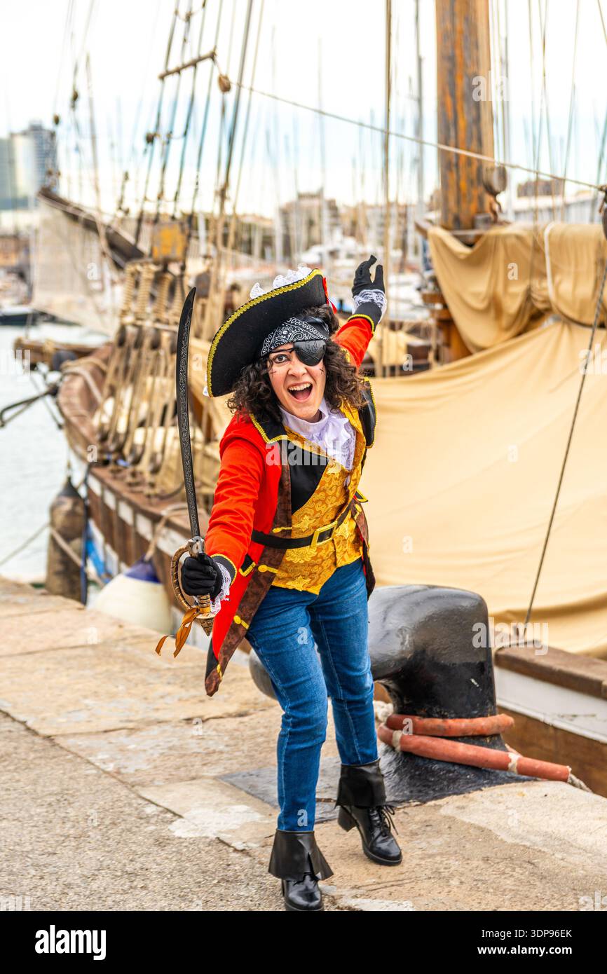 Woman dressed as a pirate captain, holding a sword and raising an arm ...