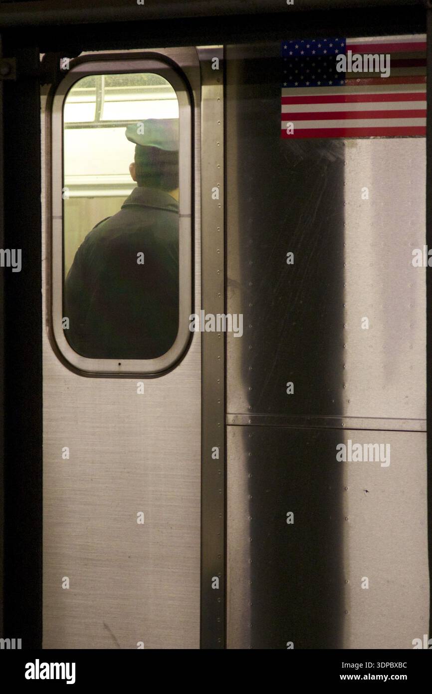 Back of an NYPD police officer seen through the window on an MTA subway ...