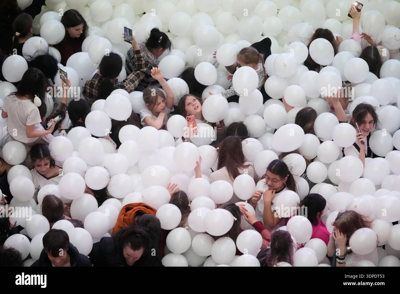 People catch air balloons cascading down in a shopping mall on ...