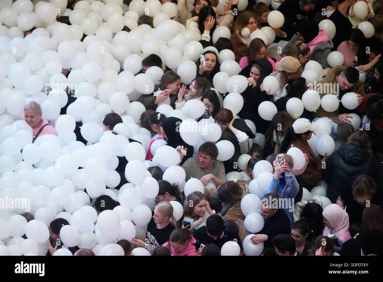 People catch air balloons cascading down in a shopping mall on ...