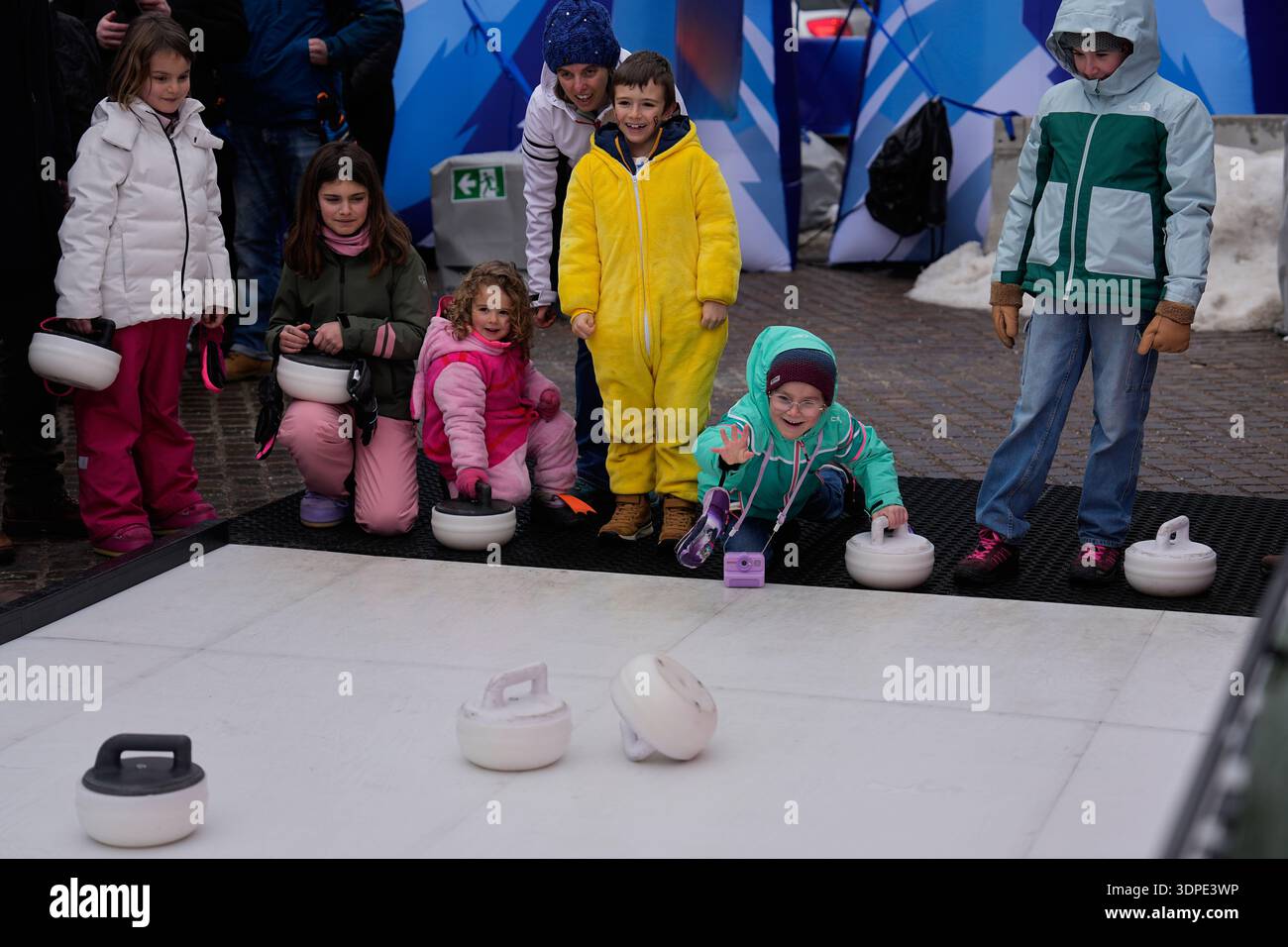 Children play a mock curling game at a promotional booth, in Cortina d ...