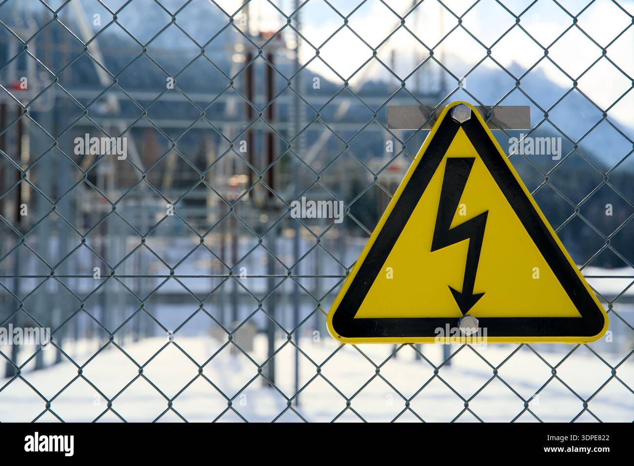 Triangular yellow high-voltage danger sign on fence, warning for ...