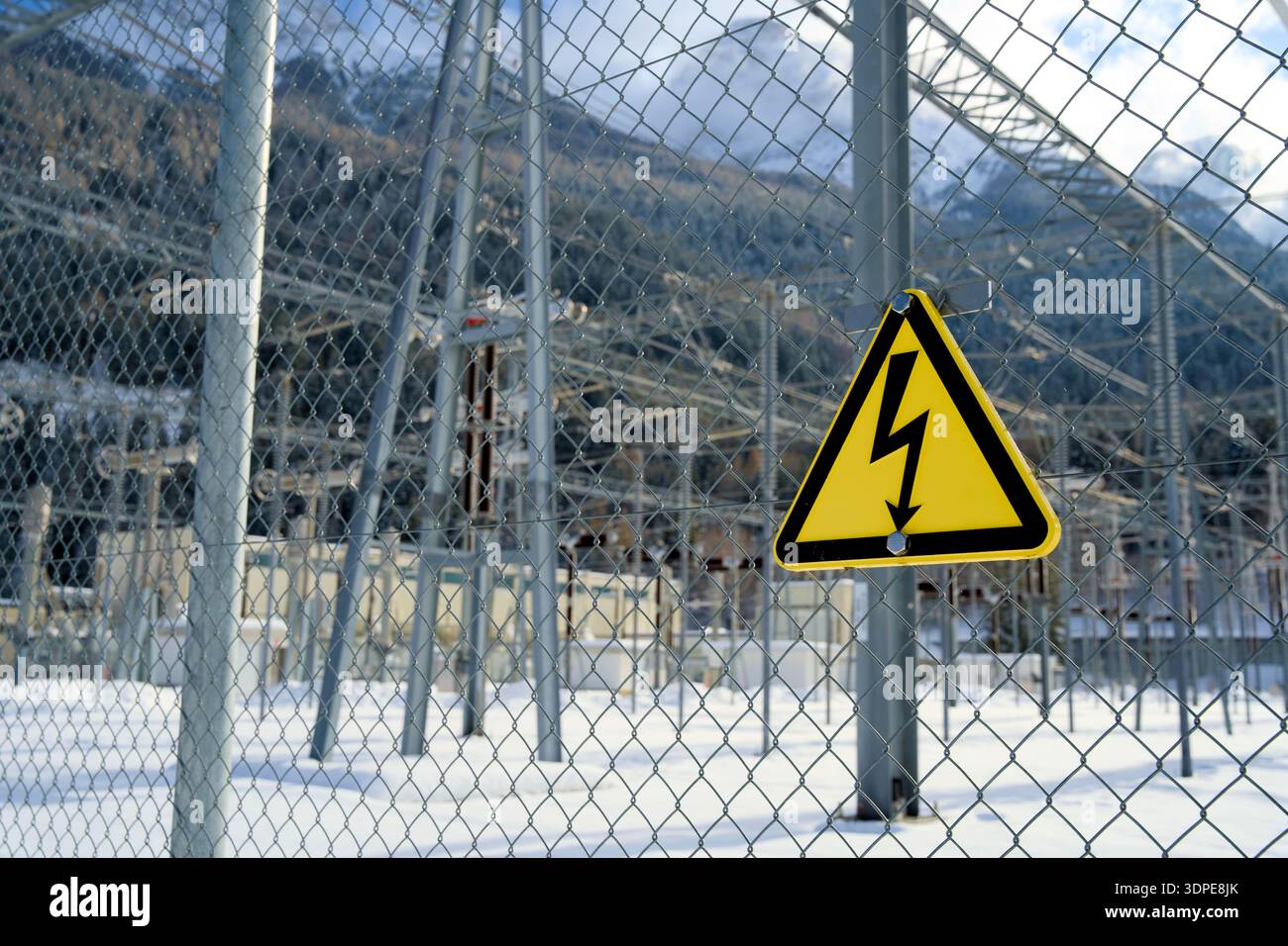 Triangular yellow high-voltage danger sign on fence, warning for ...
