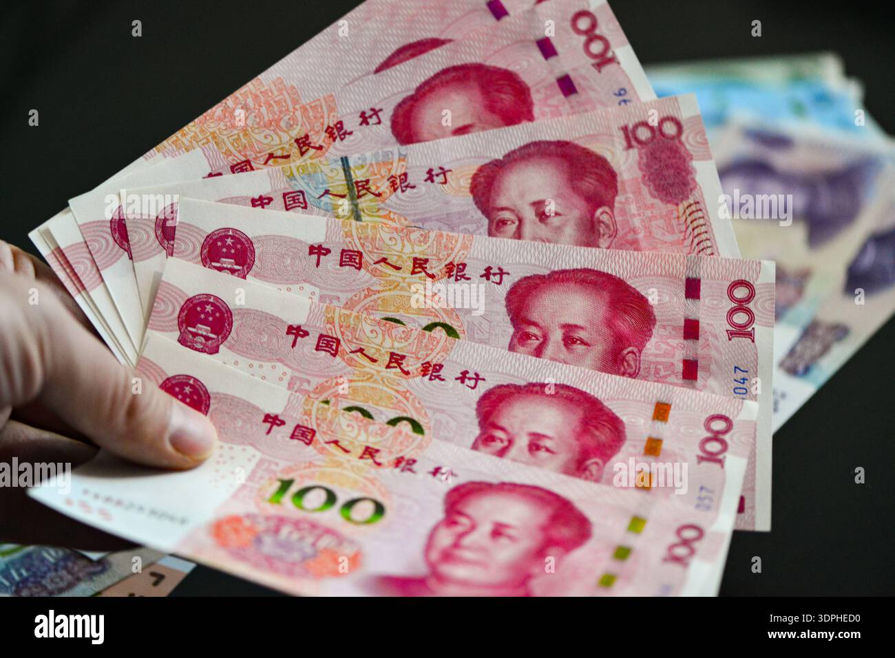 In this photo illustration, a hand fans out a stack of 100-yuan RMB ...