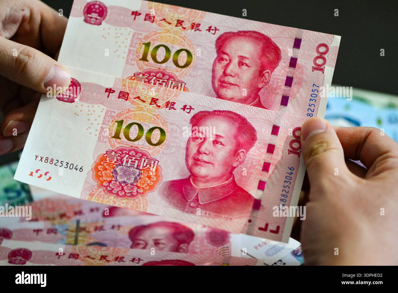 In this photo illustration, two hands hold a pair of 100-yuan RMB ...