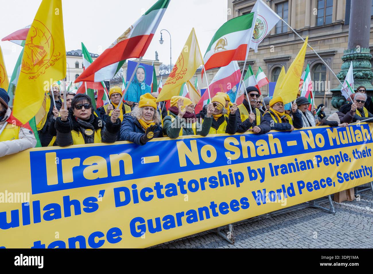 Participants wearing yellow vests and caps wave Iranian tricolor flags ...