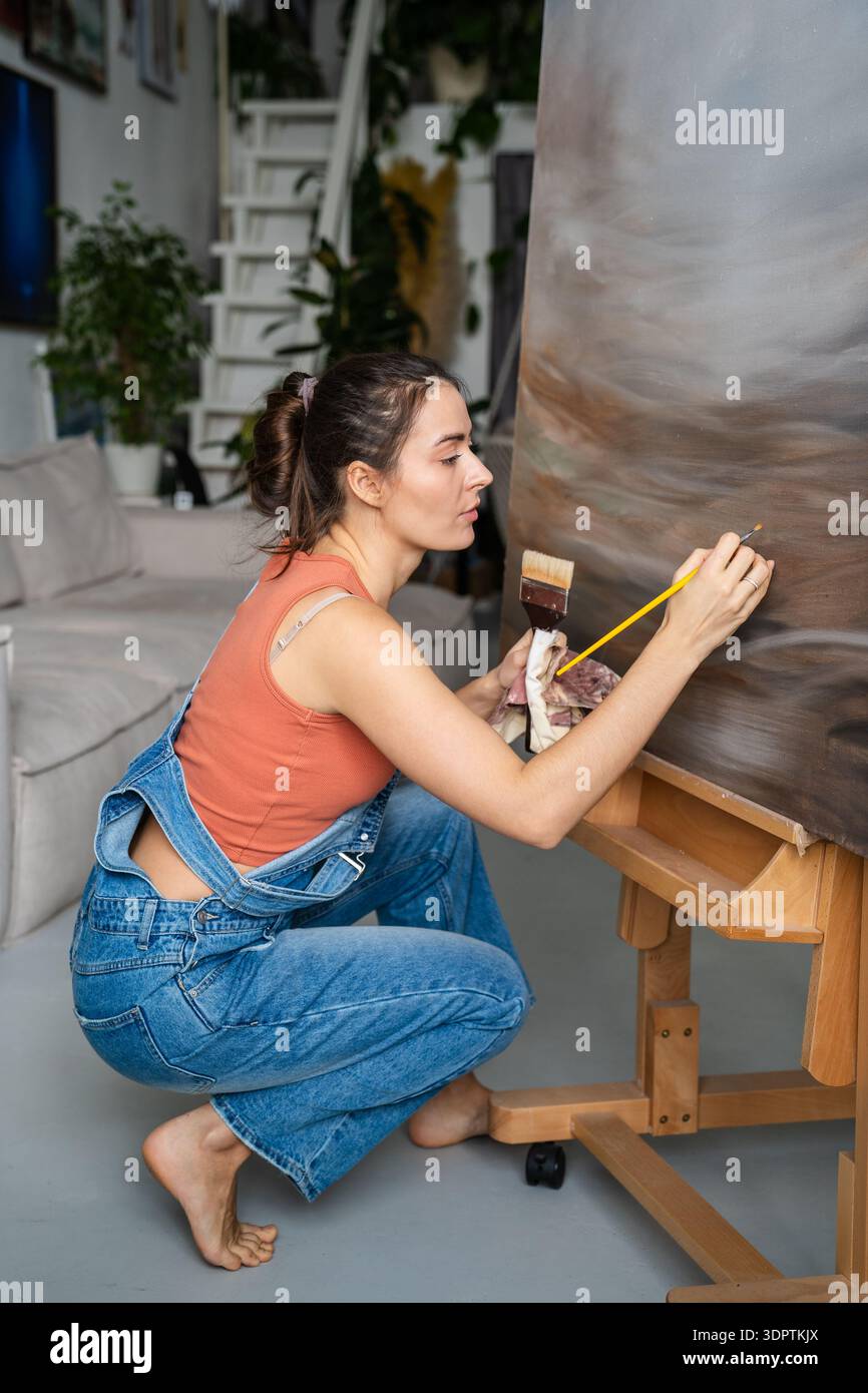 Creative female artist finishing painting picture on big canvas using ...