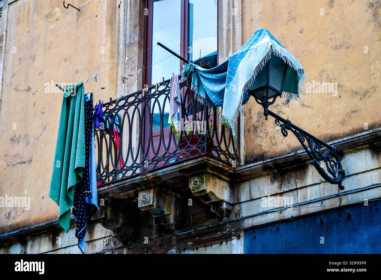 Laundry drying on wrought iron balcony of ochre building in Catania ...