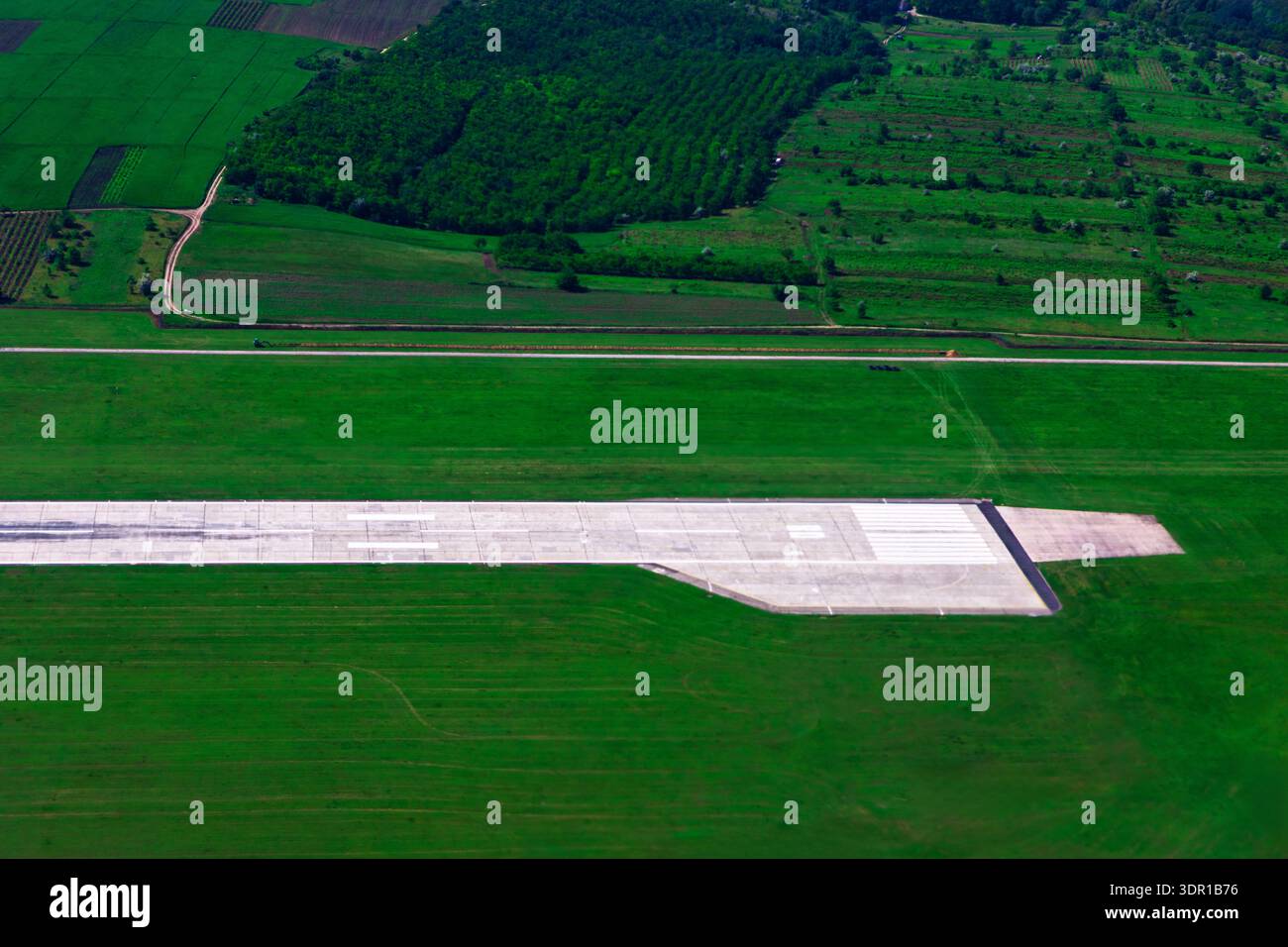 Aerial shot captures concrete runway. Airfield is surrounded by ...