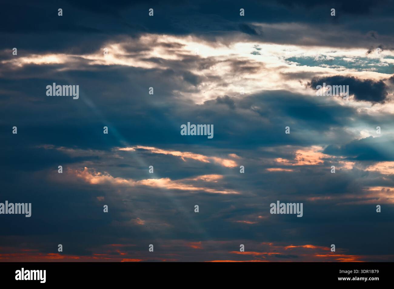 Dramatic crepuscular rays piercing through dark, layered stratocumulus ...