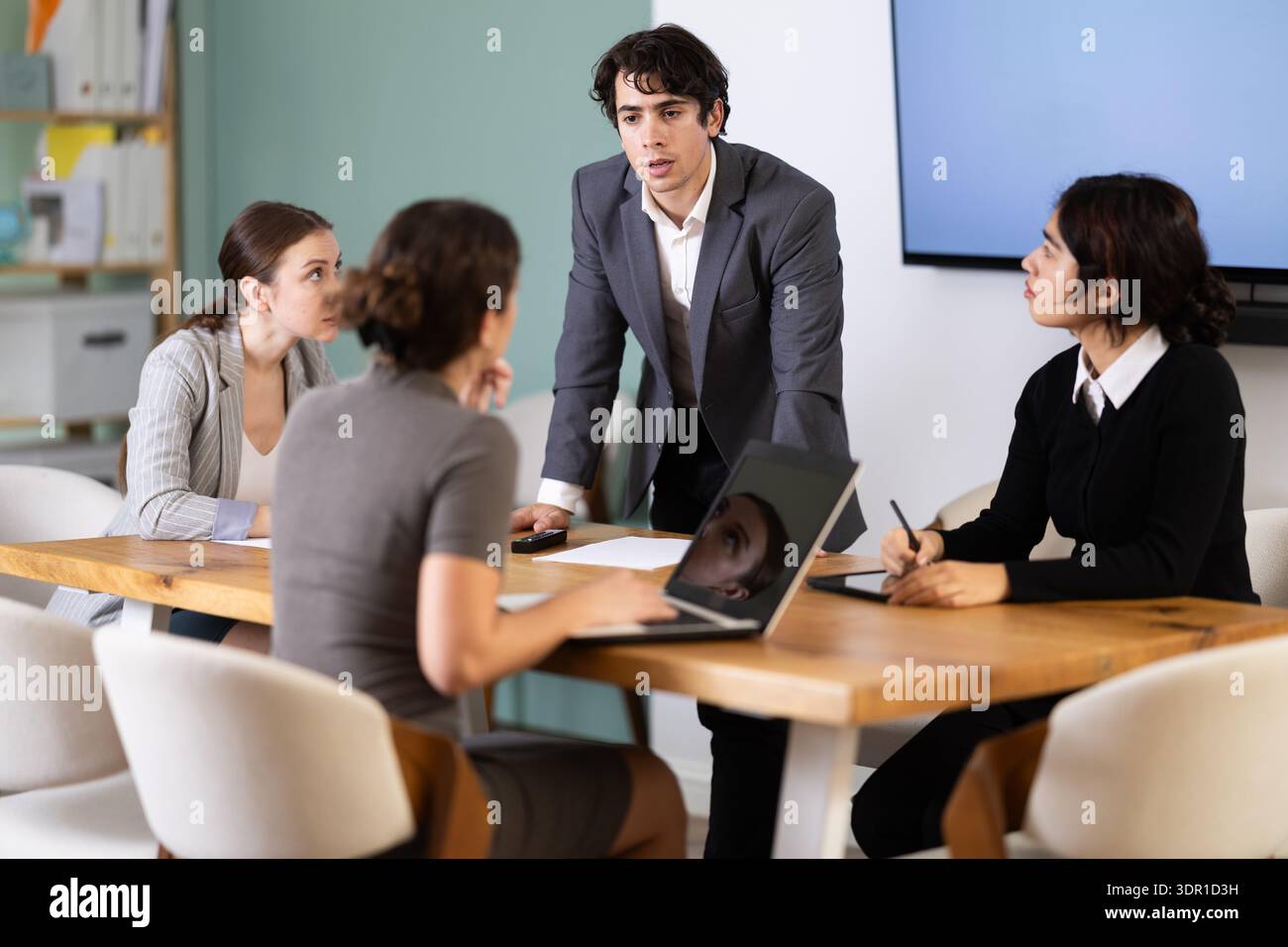 Confident young businessman standing near table where sitting ...