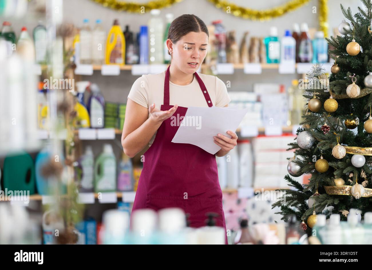 Bewildered girl seller work with document, looks at report and is upset ...