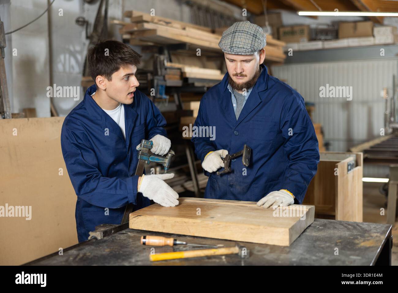 Young men fixing wooden board with clamp Stock Photo - Alamy