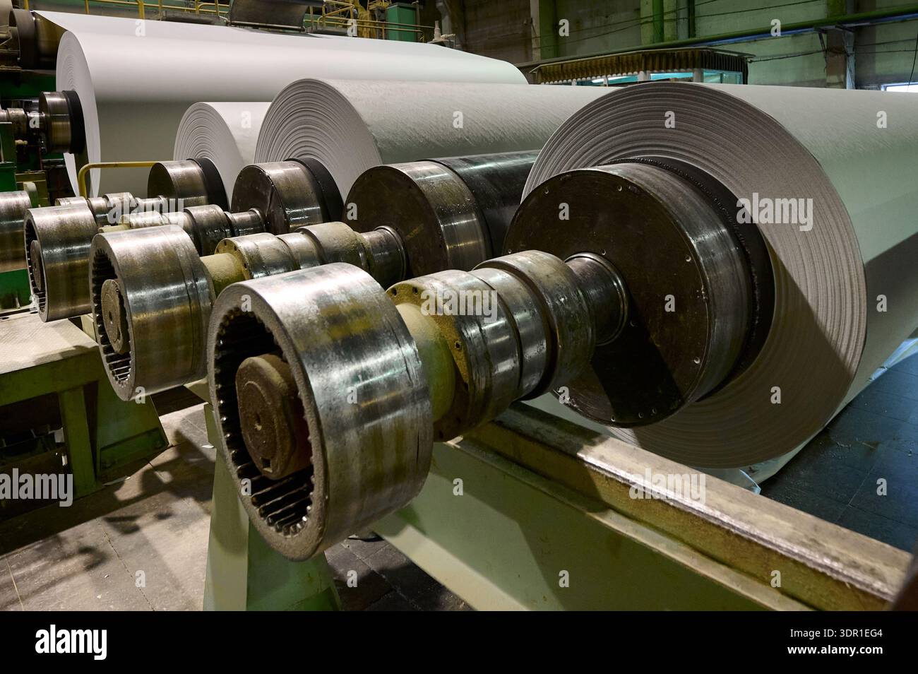 Paper rolls being processed in a manufacturing plant during daylight ...