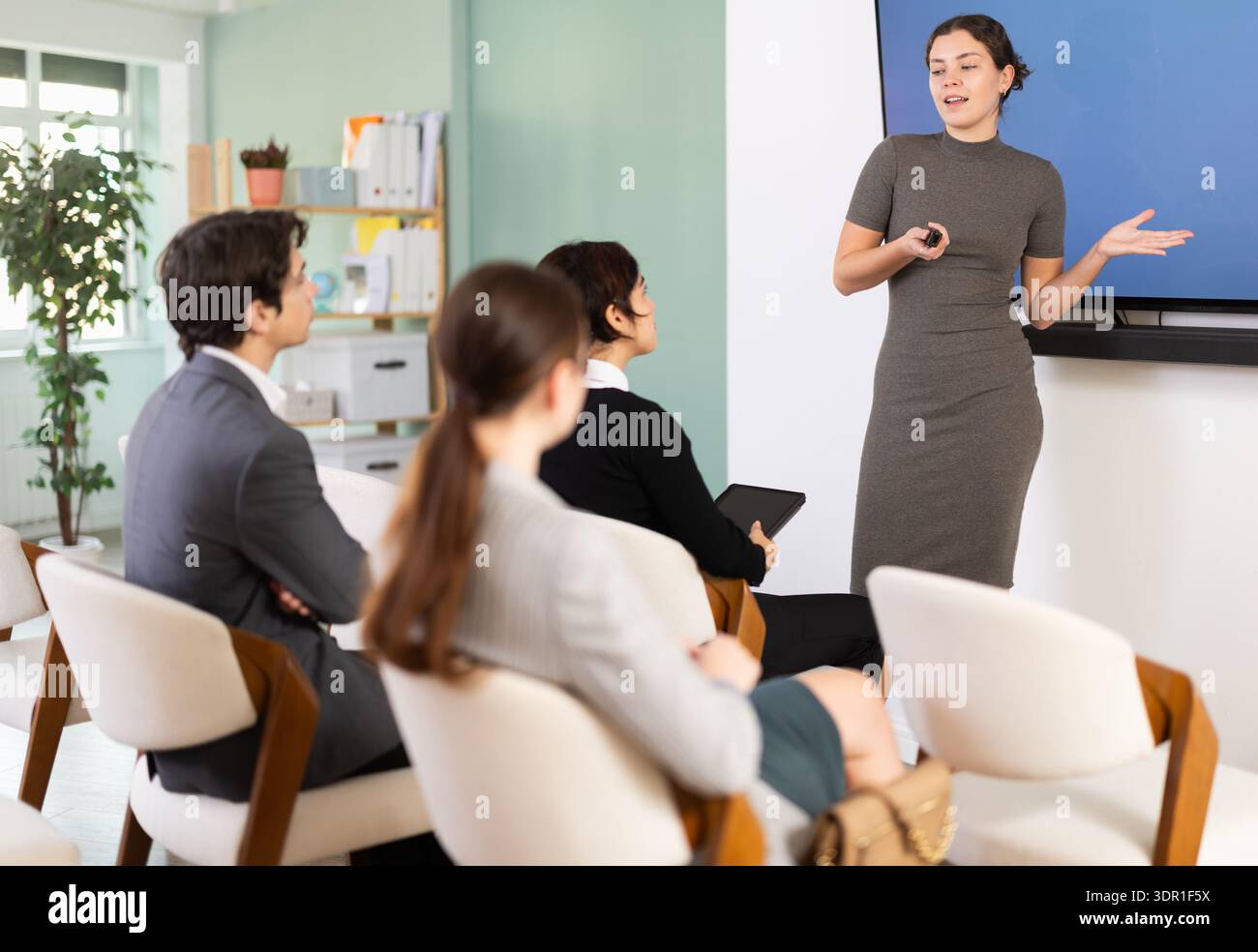Young woman presenting with remote control in meeting room Stock Photo ...