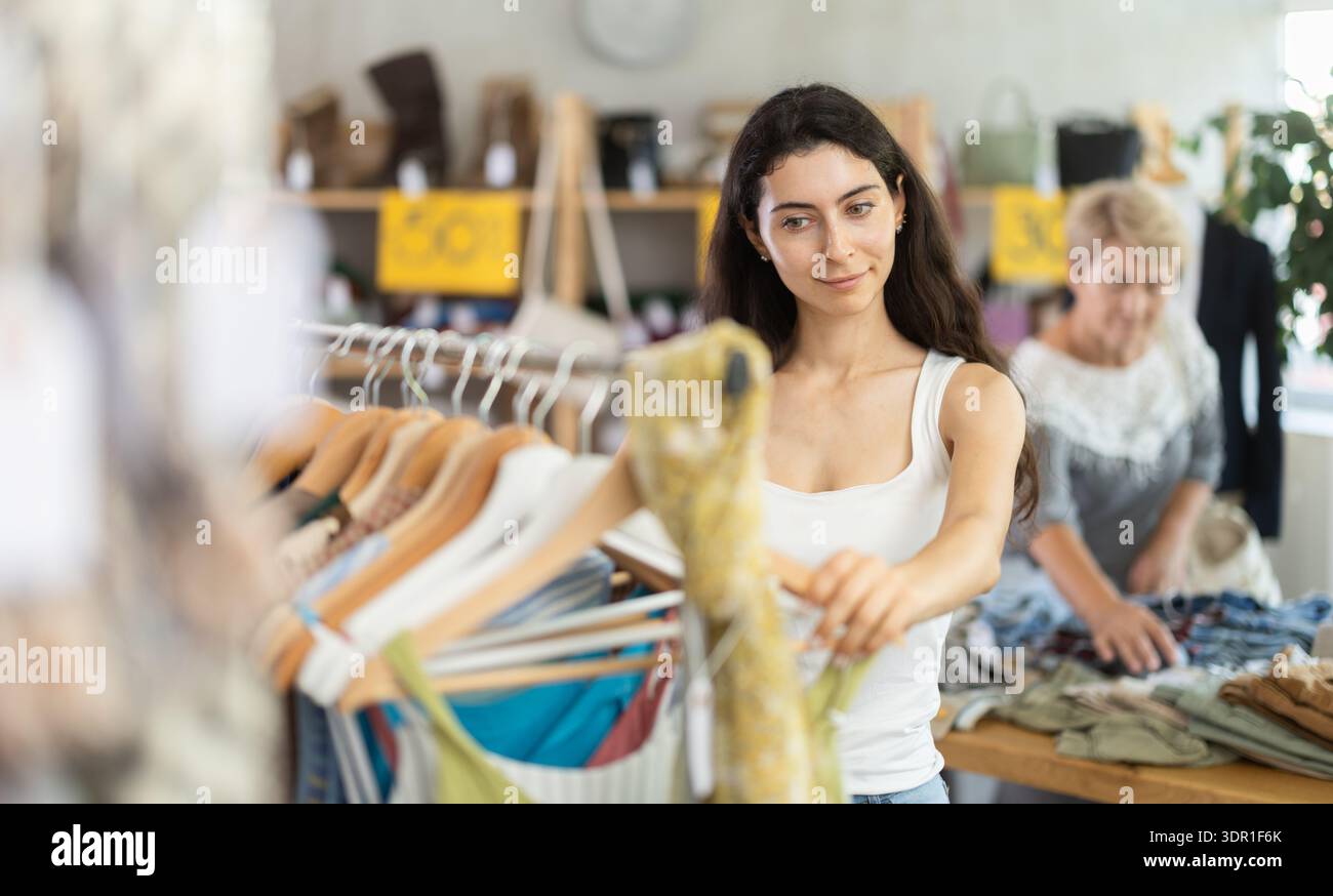 Young woman customer elect something summer clothes in store. Female ...