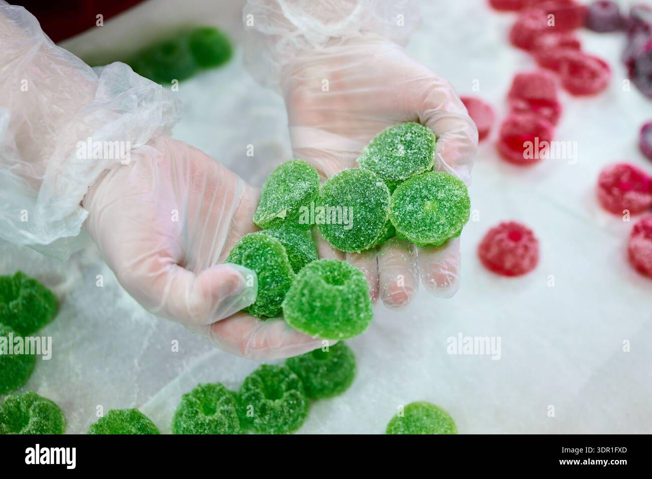 Hands holding vibrant green marmalade confectionery with colorful ...